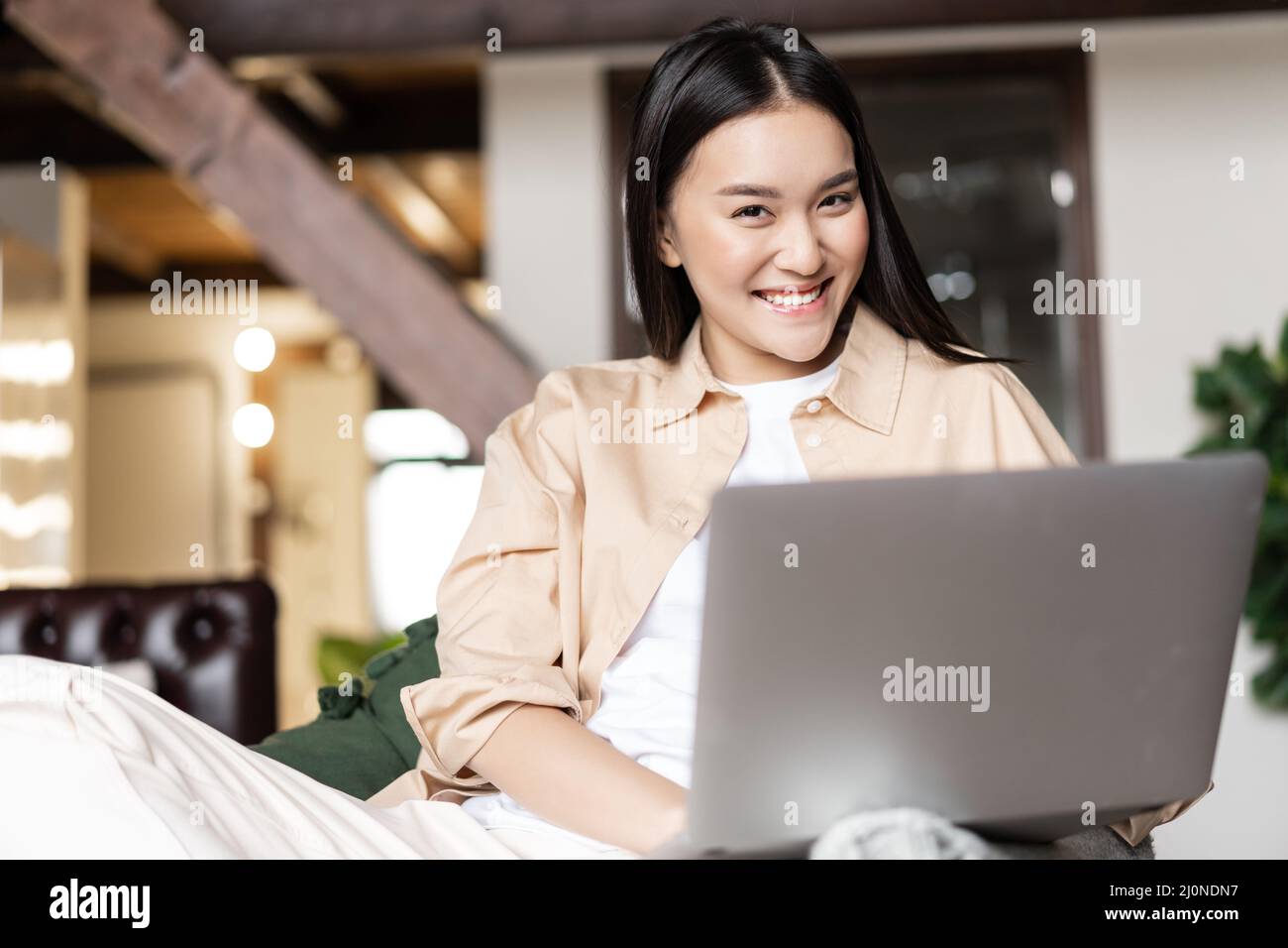 Smiling asian girl using laptop computer at home, freelancer working ...