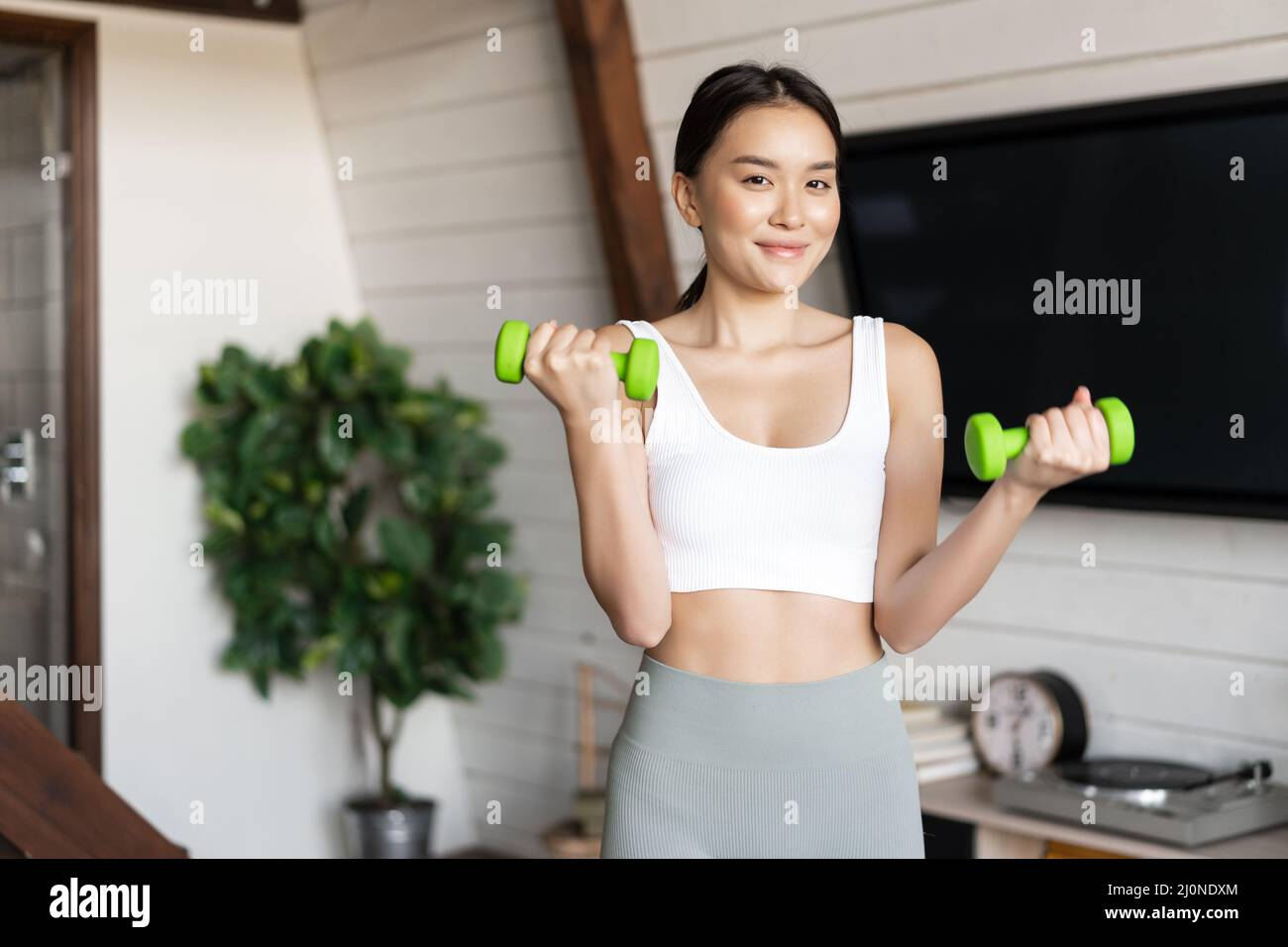Fitness asian girl doing workout at home in living room, lifting ...