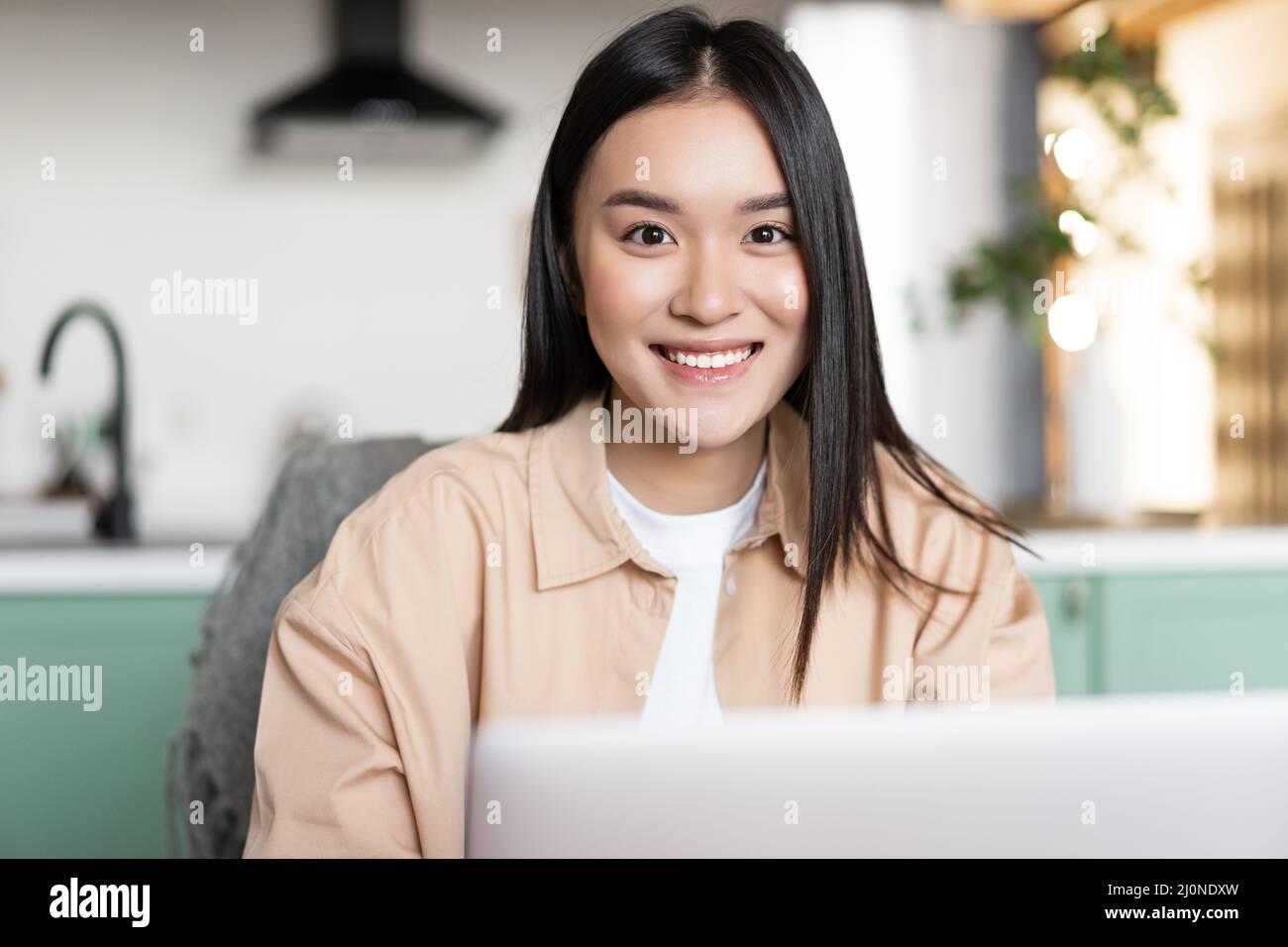 Freelance asian girl sitting at home and working with laptop, smiling ...