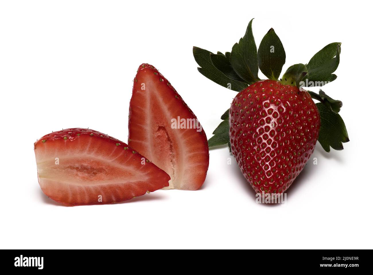 Close up of ripe strawberry with green leaves next to halves cut in the ...