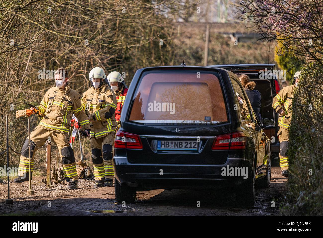 Bremen, Germany. 20th Mar, 2022. Firefighters walk past a hearse to the ...