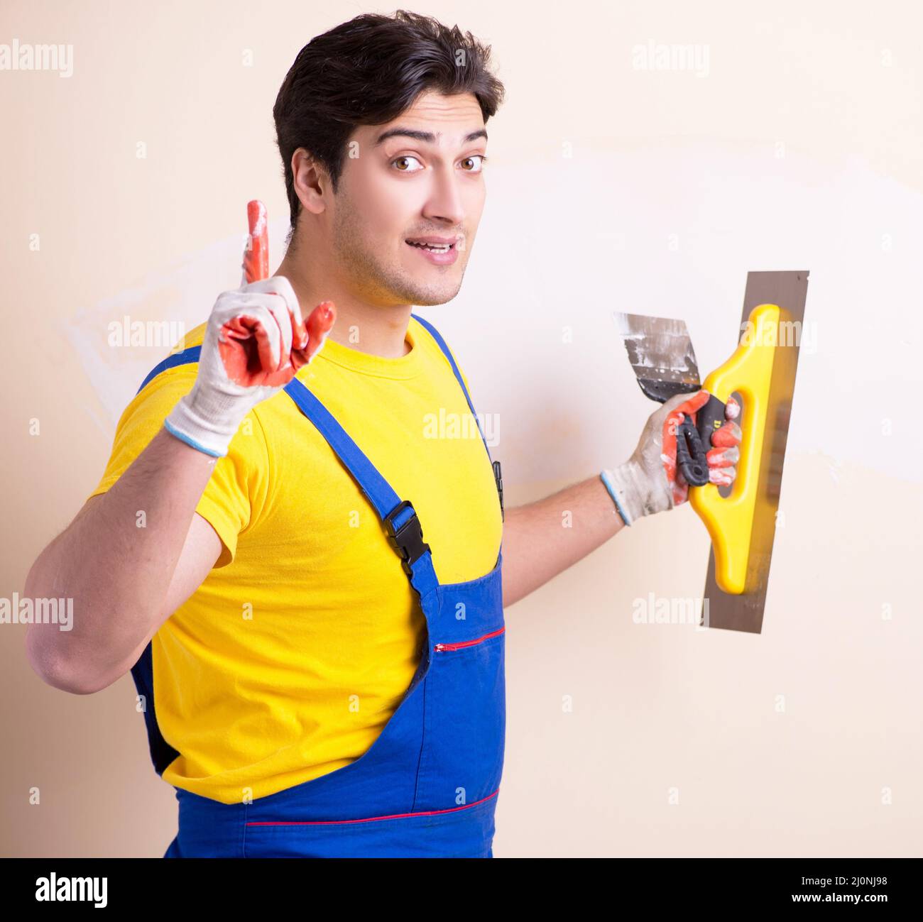 Young contractor employee applying plaster on wall Stock Photo - Alamy