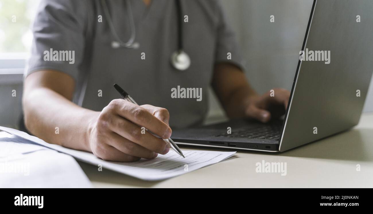 Side view doctor with stethoscope working laptop writing paper . High ...