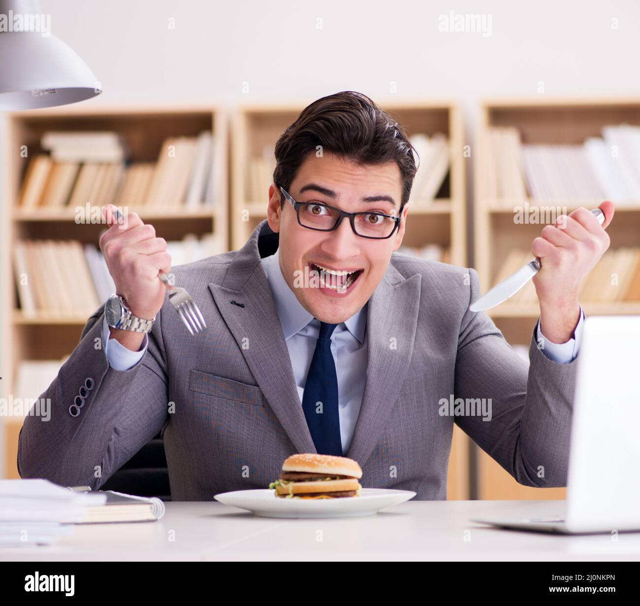 Hungry funny businessman eating junk food sandwich Stock Photo - Alamy
