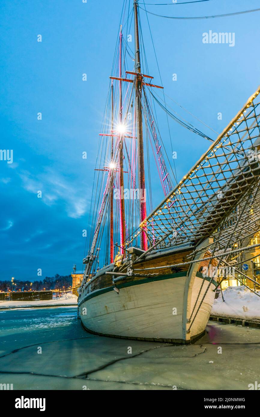 Wooden sailing ship moored in port during a frosty winter night ...