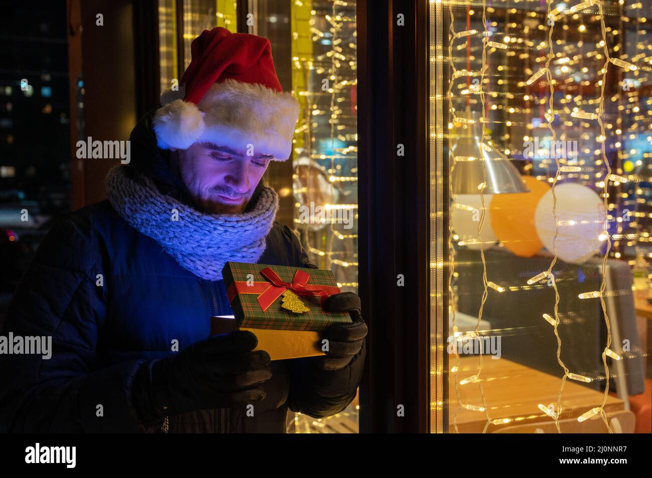 Man in Santas hat looking and dreaming in illuminated shop window Stock ...