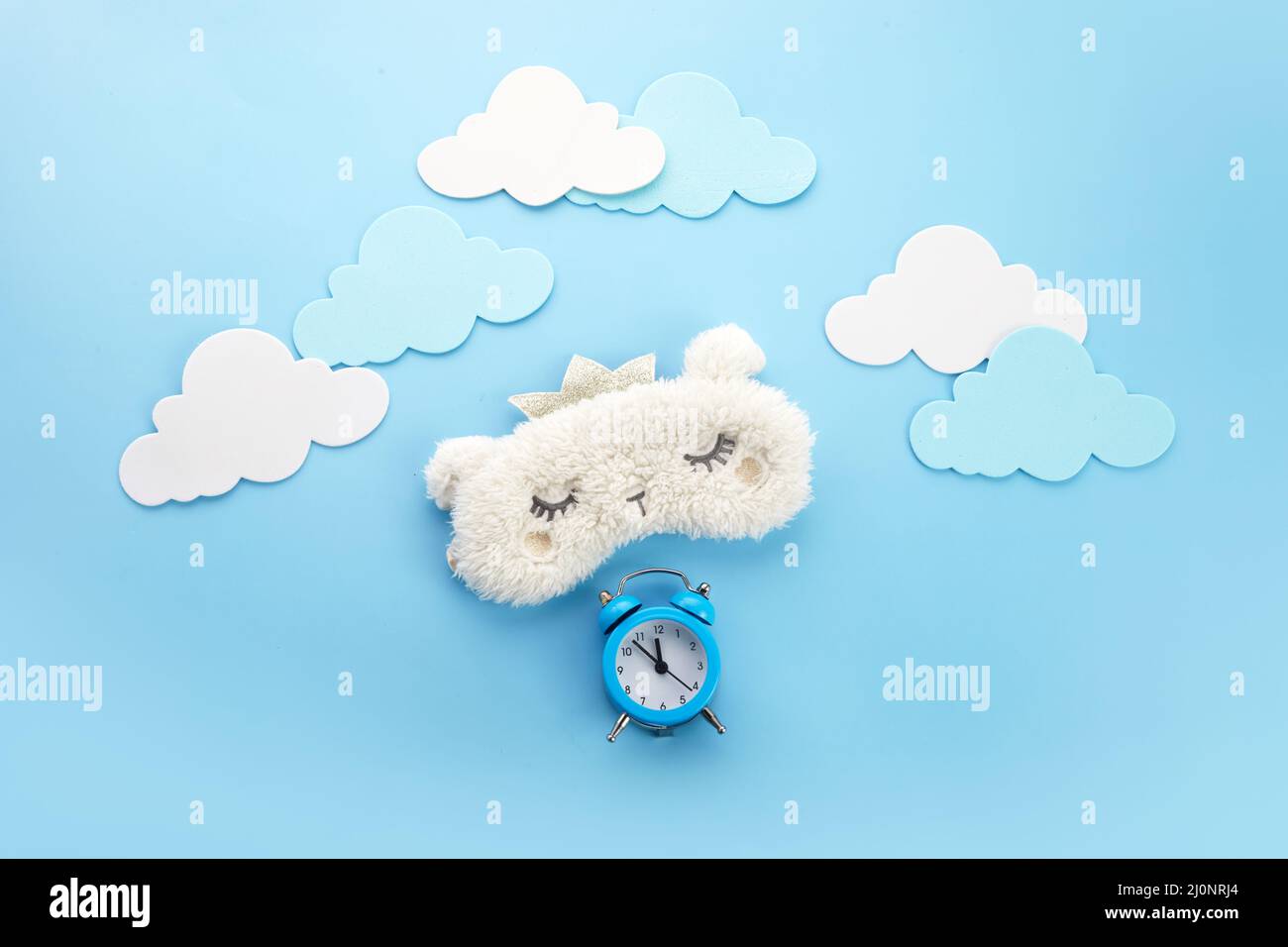 Sleeping eye mask and alarm clock on blue background with clouds ...