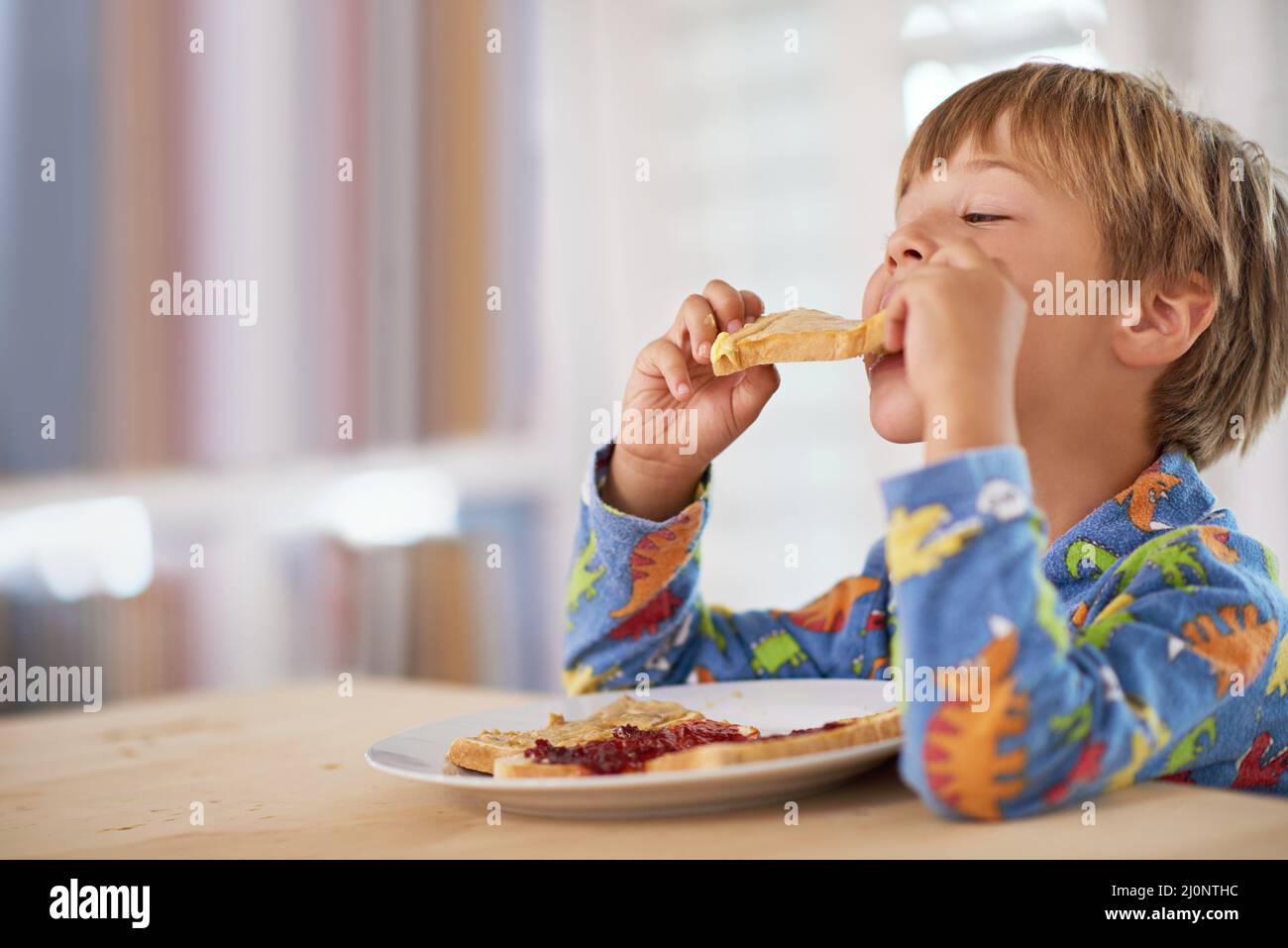 Tasty toast. A cute little boy eating breakfast Stock Photo - Alamy