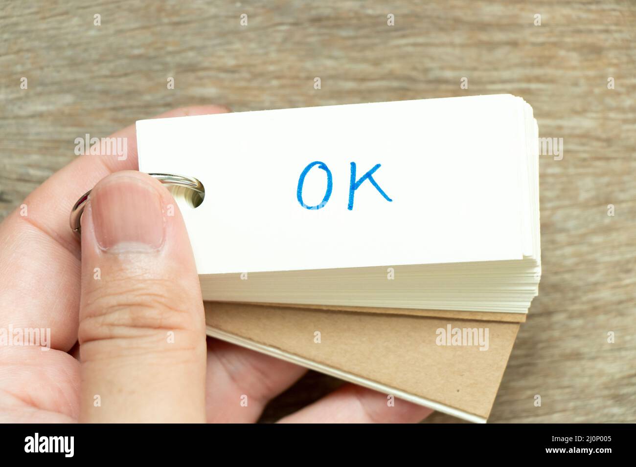 Man hold the flash card with handwriting word OK on wood background ...