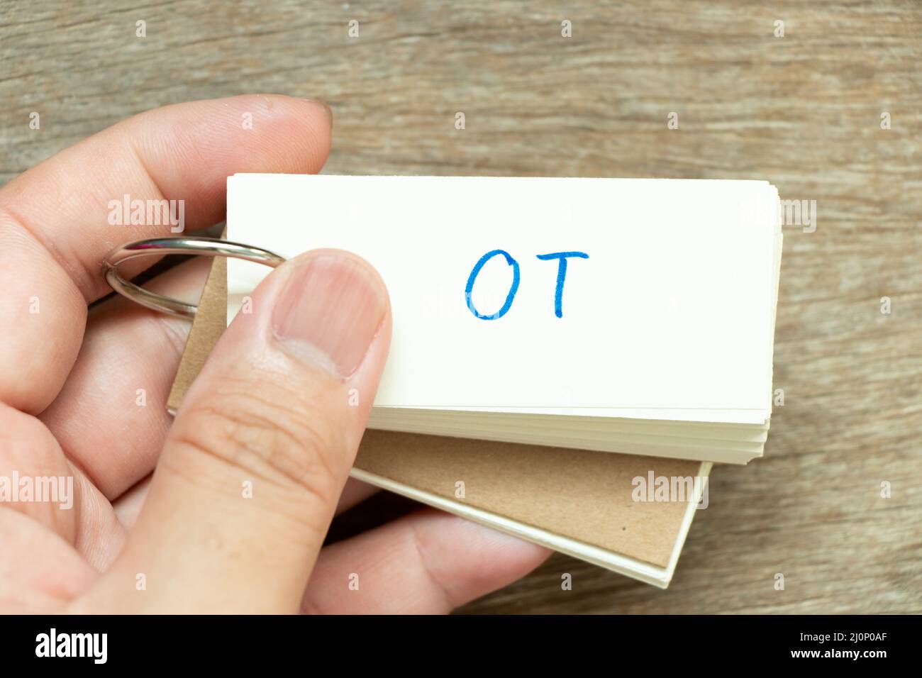 Man hold the flash card with handwriting word OT (abbreviation for ...