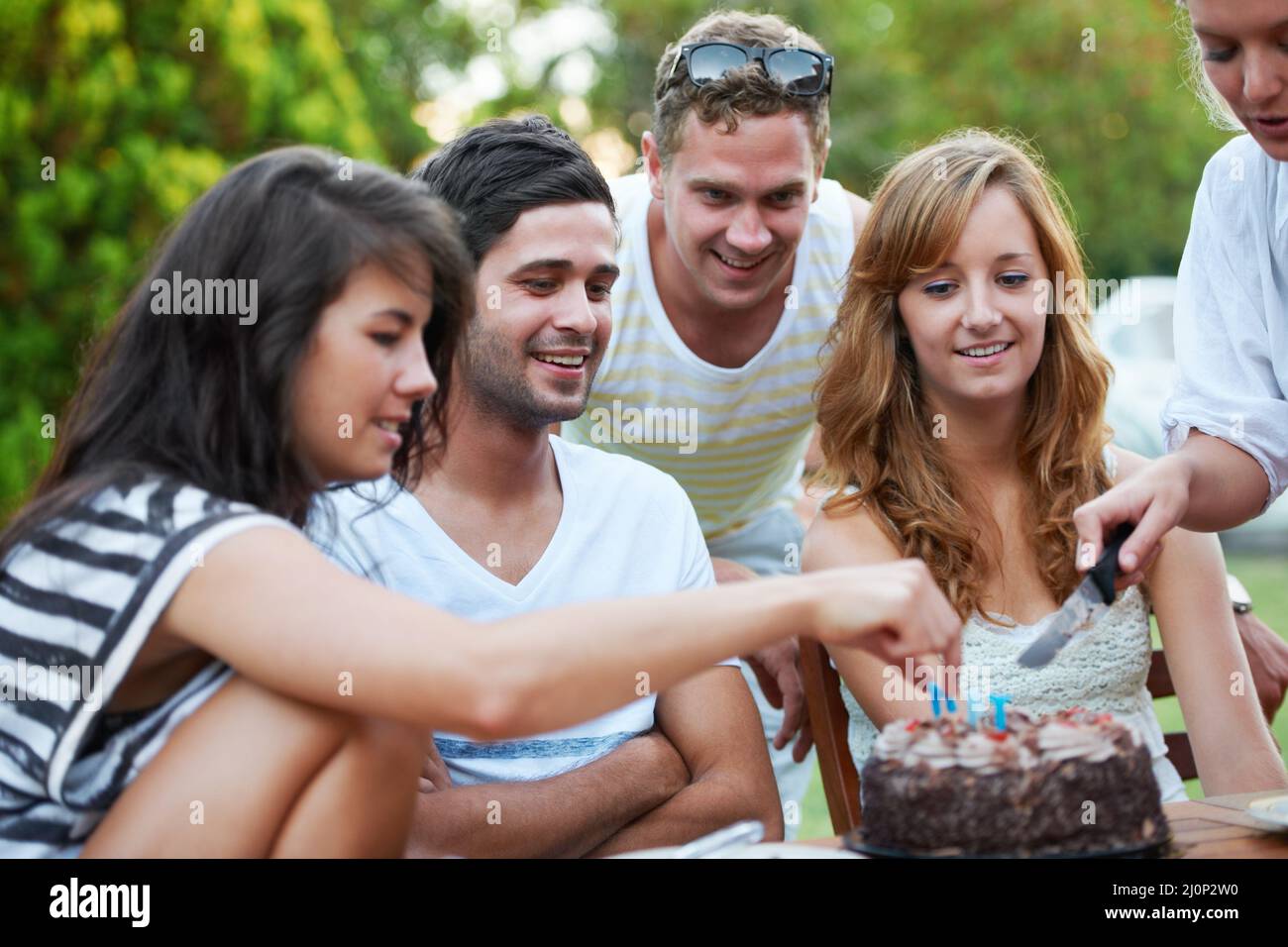 Birthdays are all about sharing. Smiling young teen friends celebrating ...