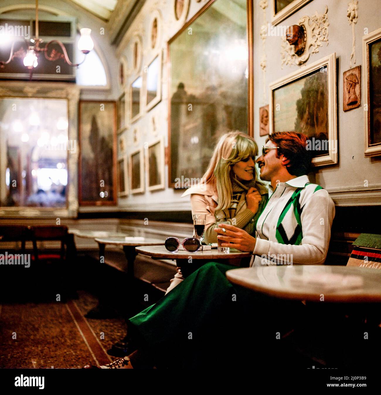 Vintage Rome 1970s, stylish couple having a drink and flirting inside ...