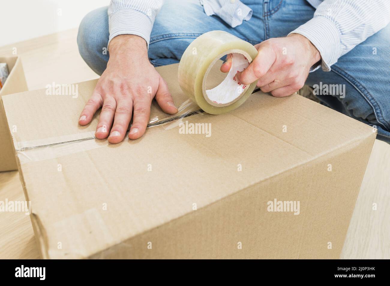 Young man sealing cardboard box with tape big moving. High quality and ...