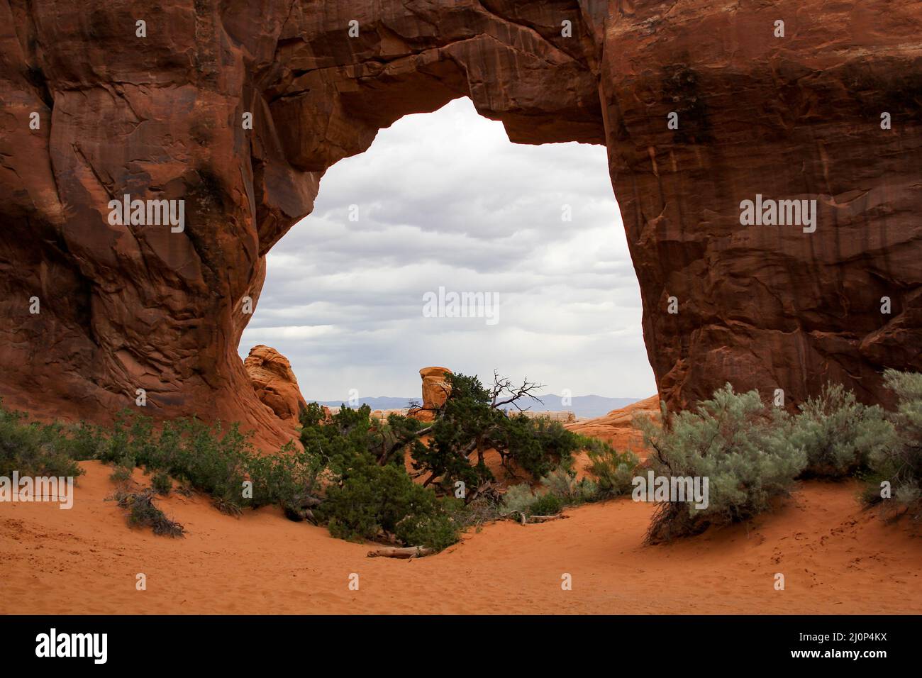 Beautiful sandstone arch with white clouds visible from the background ...