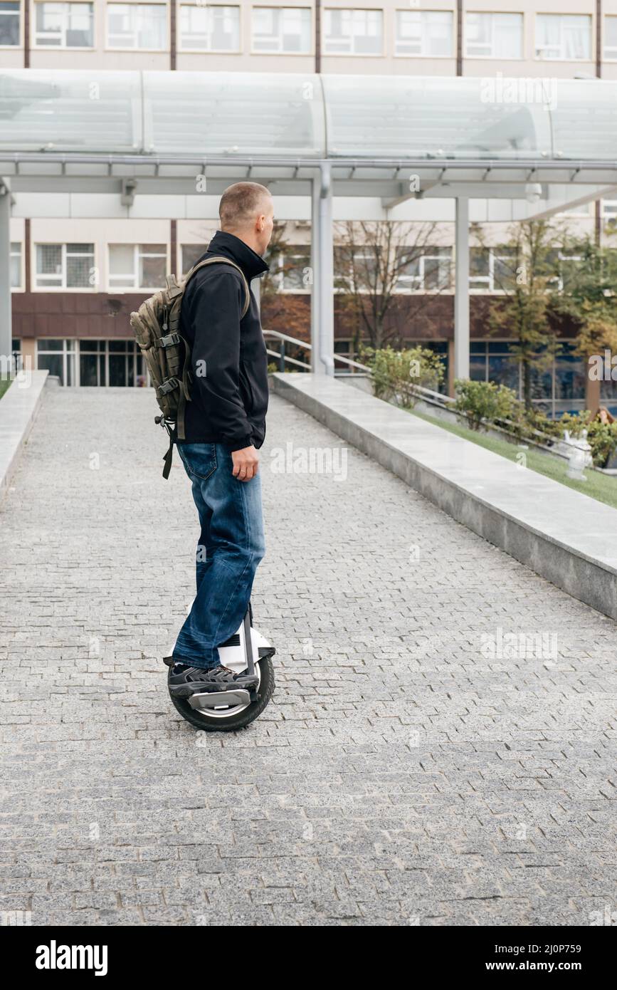 Man riding fast on electric unicycle on city street. Mobile portable ...