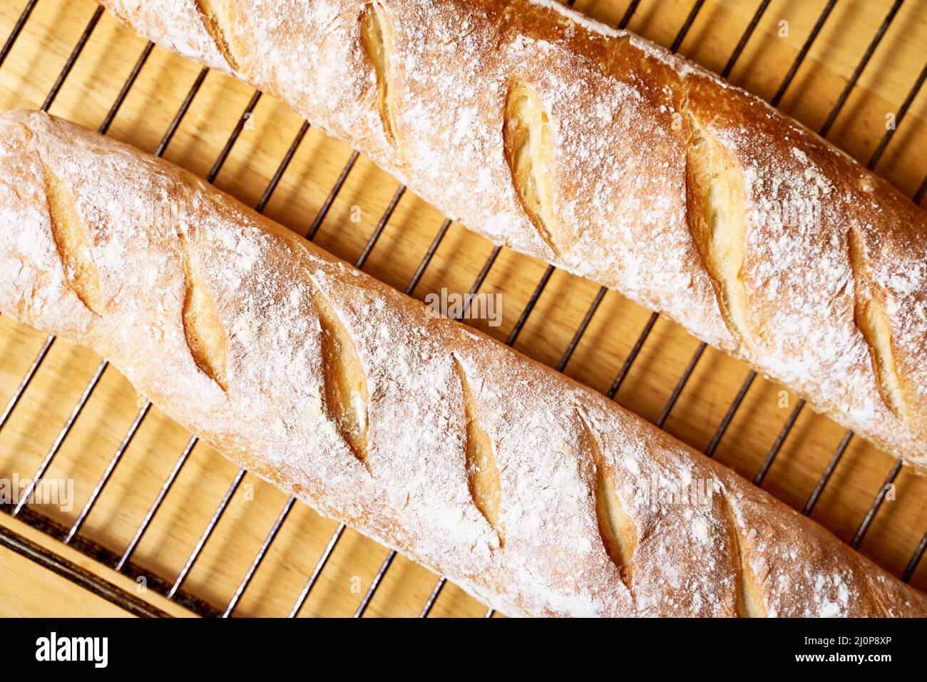 Fresh baked homemade crusty bread baguette. Two loaves cool on metal ...