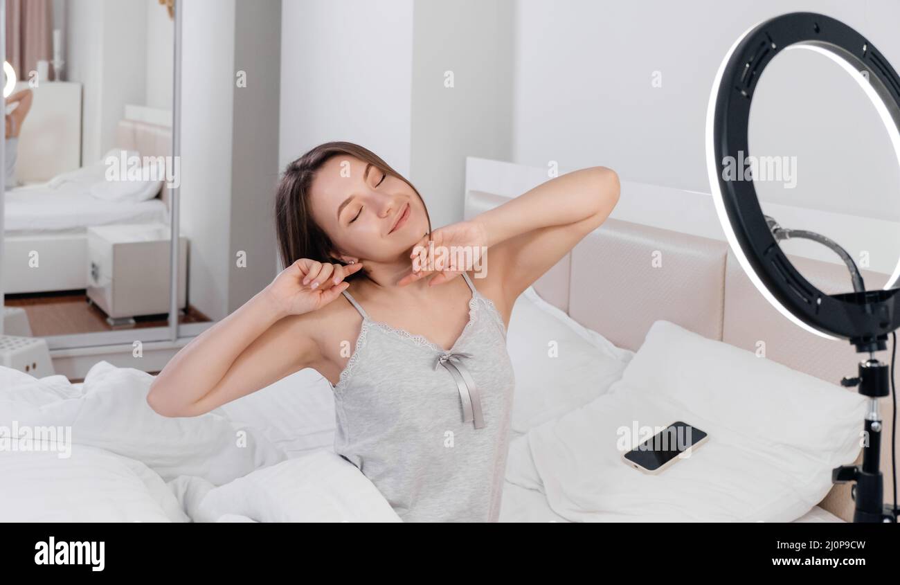 Pretty young smiling Caucasian woman waking up in the morning and ...