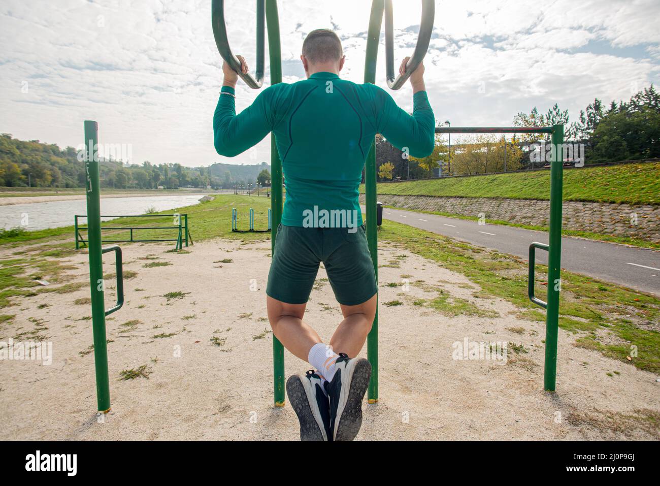 Attractive and handsome string guy is pulling up on the bars outside ...