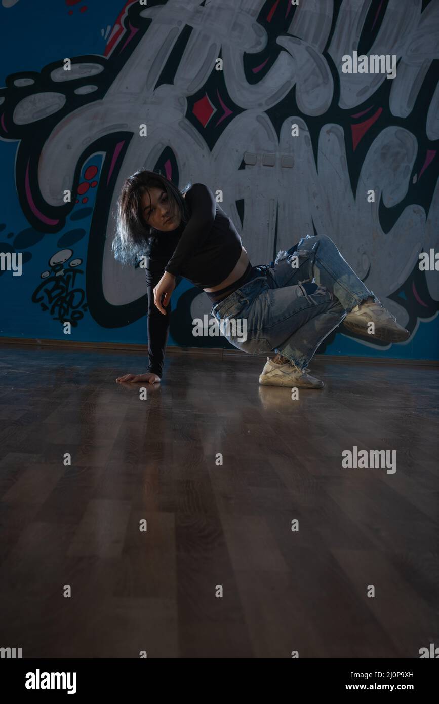Female dancer in activewear squatting on the floor of modern dance ...
