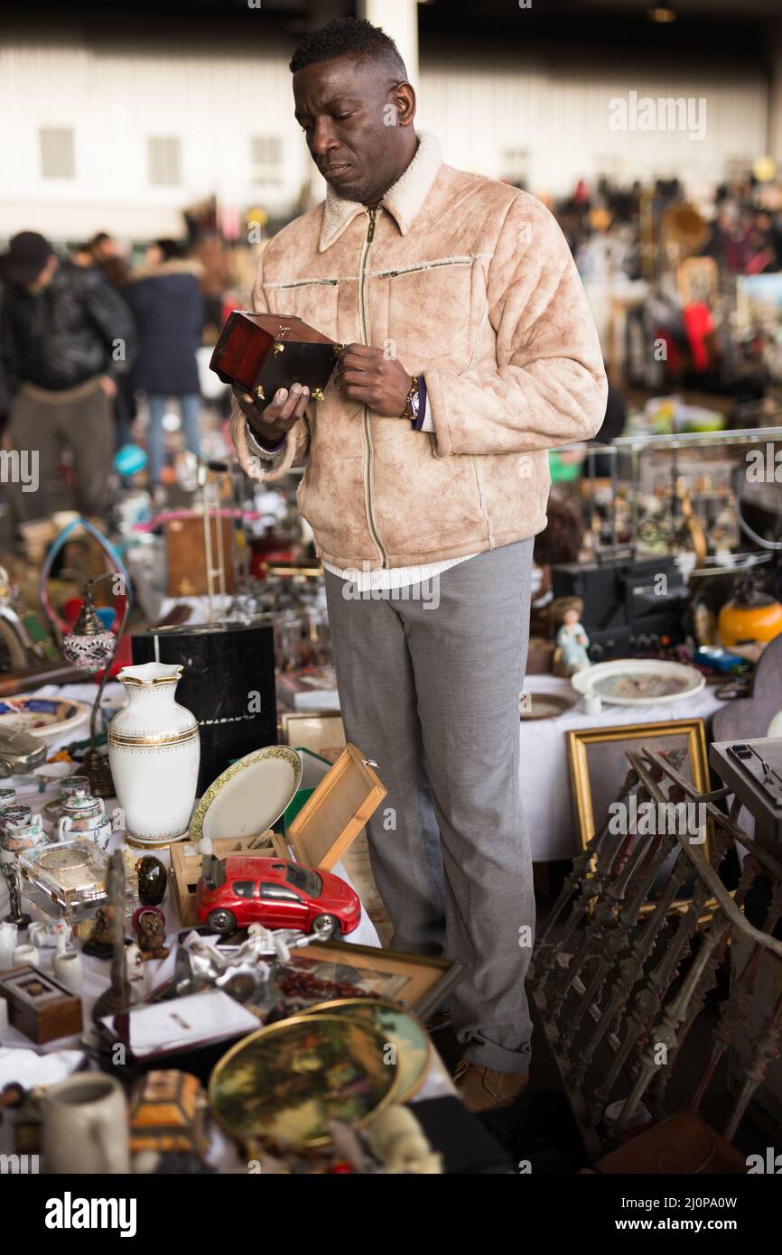ordinary Afro-American guy considers things sacond hands on flea market ...