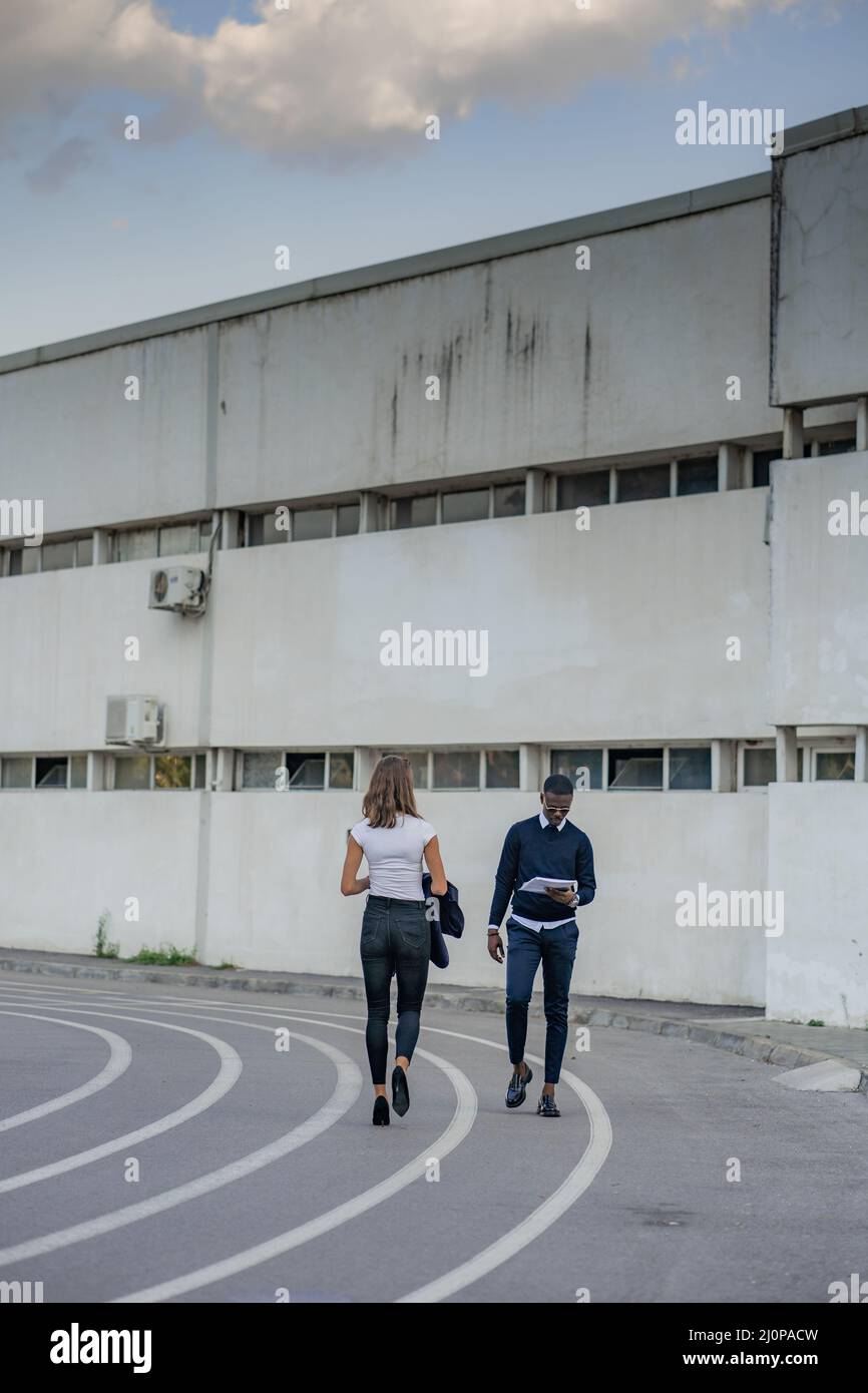 Two multiracial business people are passing each other while walking ...