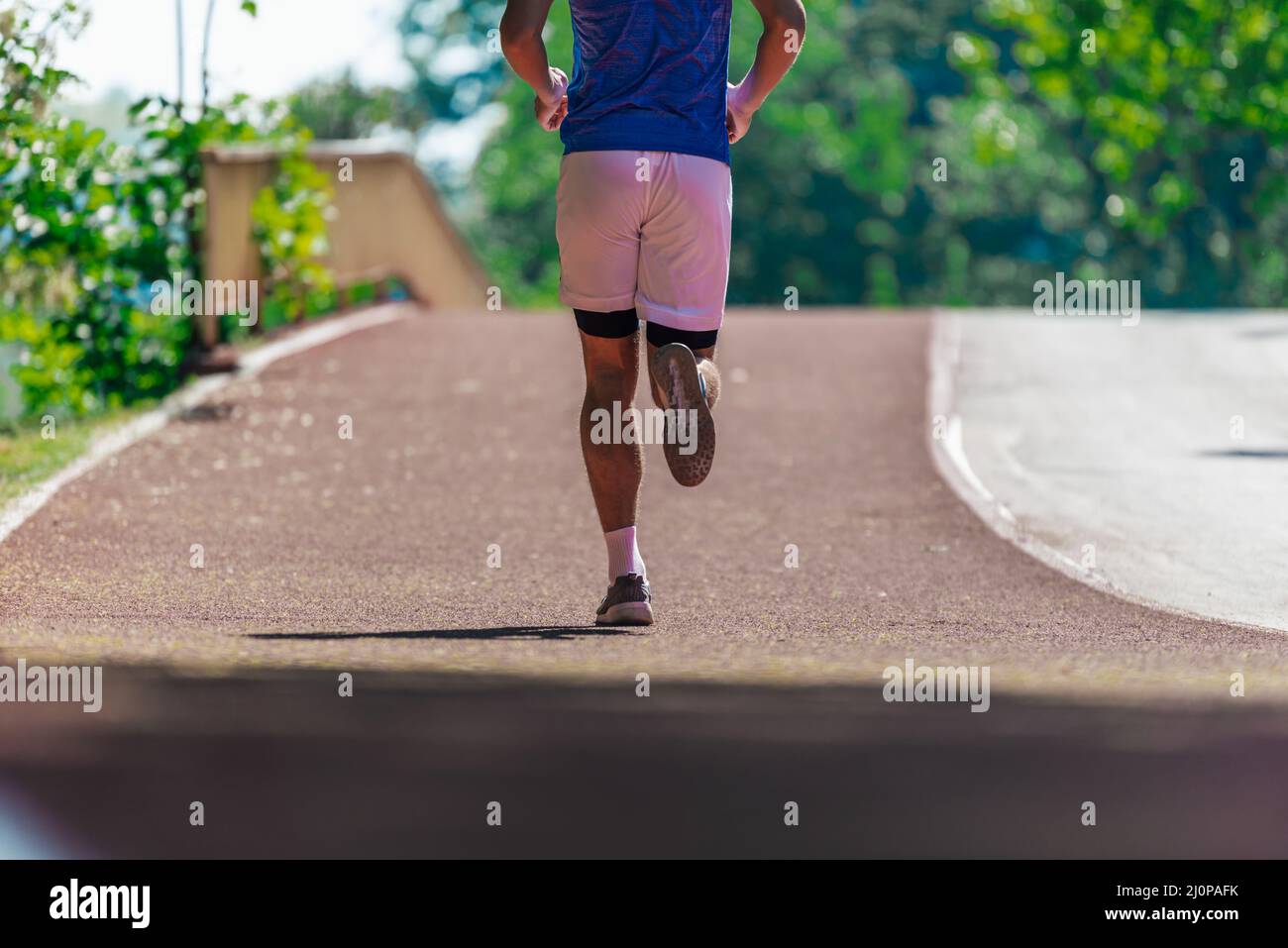 Athletic young man running on the race track in a sports park Stock ...