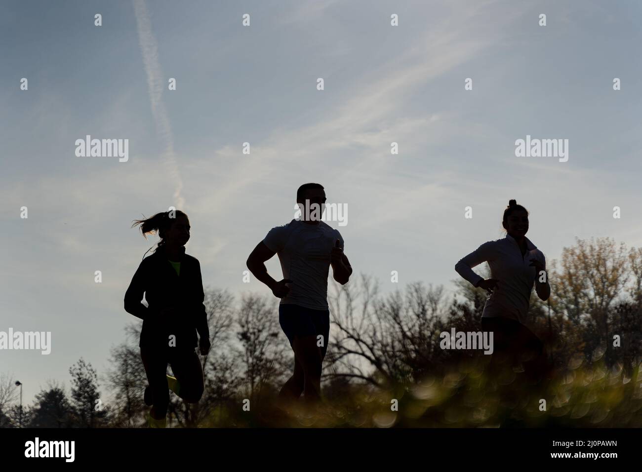 Three amazing and fit friends are running and smiling, silhouettes ...