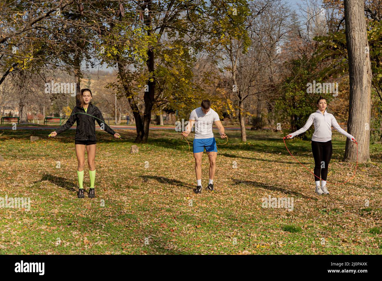 Three attractive and beautiful fit friends are jumping on the rope ...