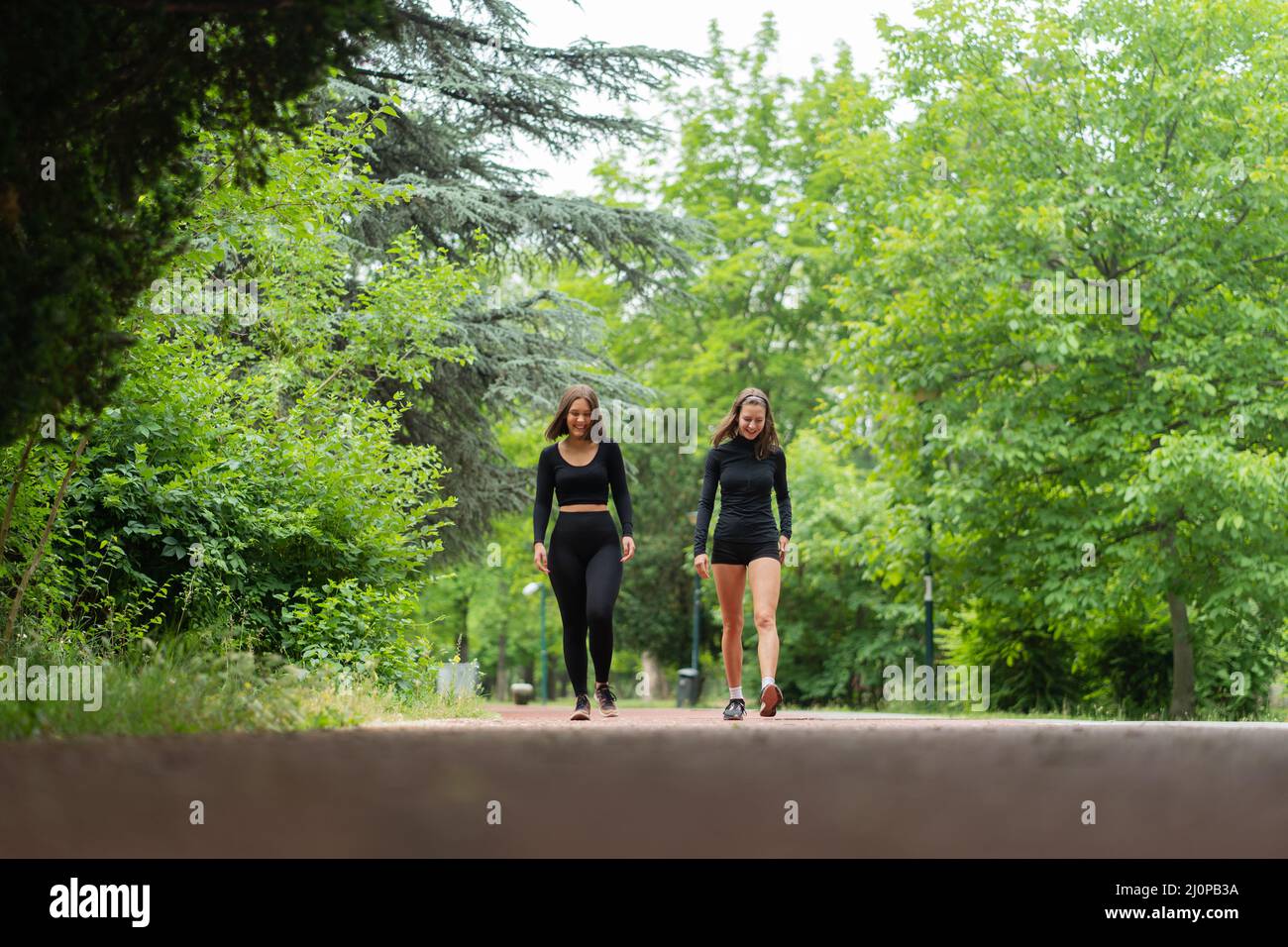 Two attractive young girls are smiling and talking while walking Stock ...