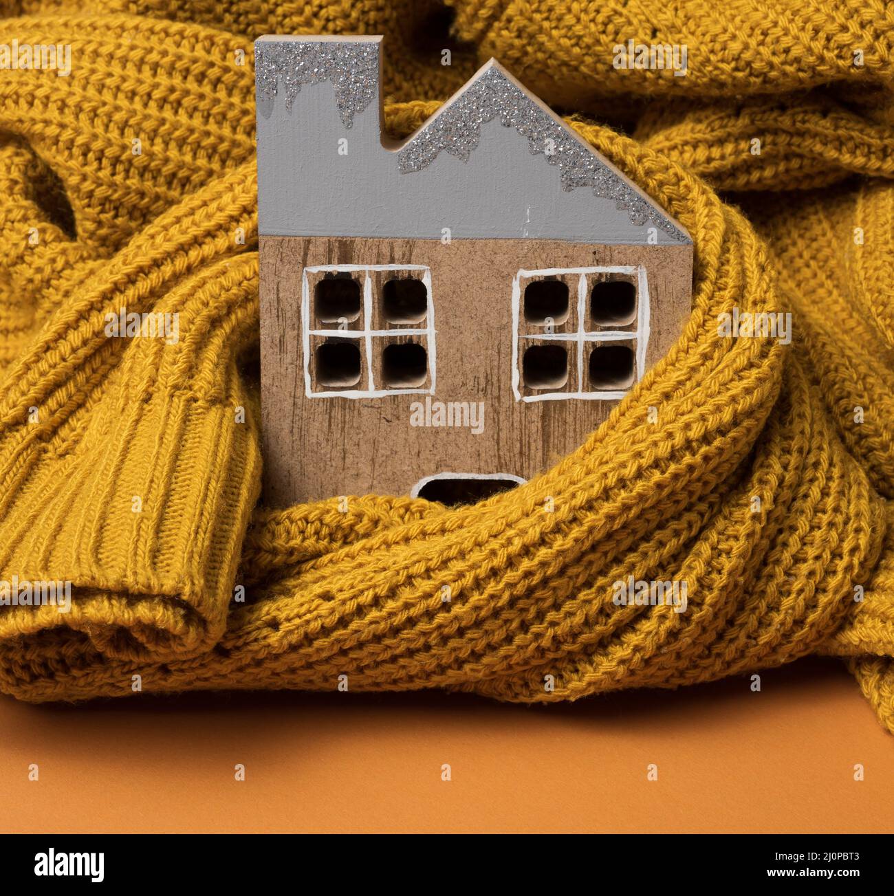Wooden model of the house is wrapped in a warm knitted sweater. Loan ...