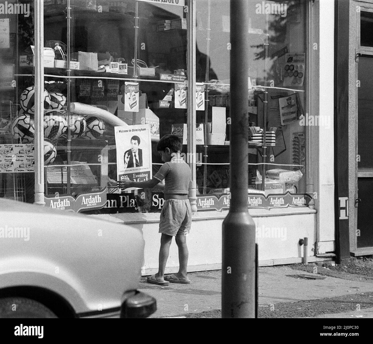 A young boy puts up a Muhammad Ali poster on a shop window in ...