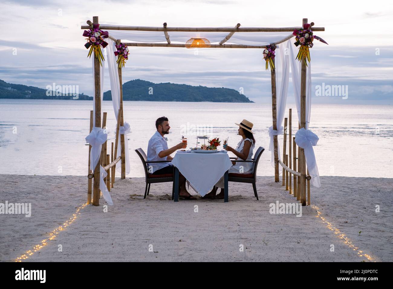 Romantic dinner on the beach, couple man and woman mid age having a romantic dinner on the beach ...