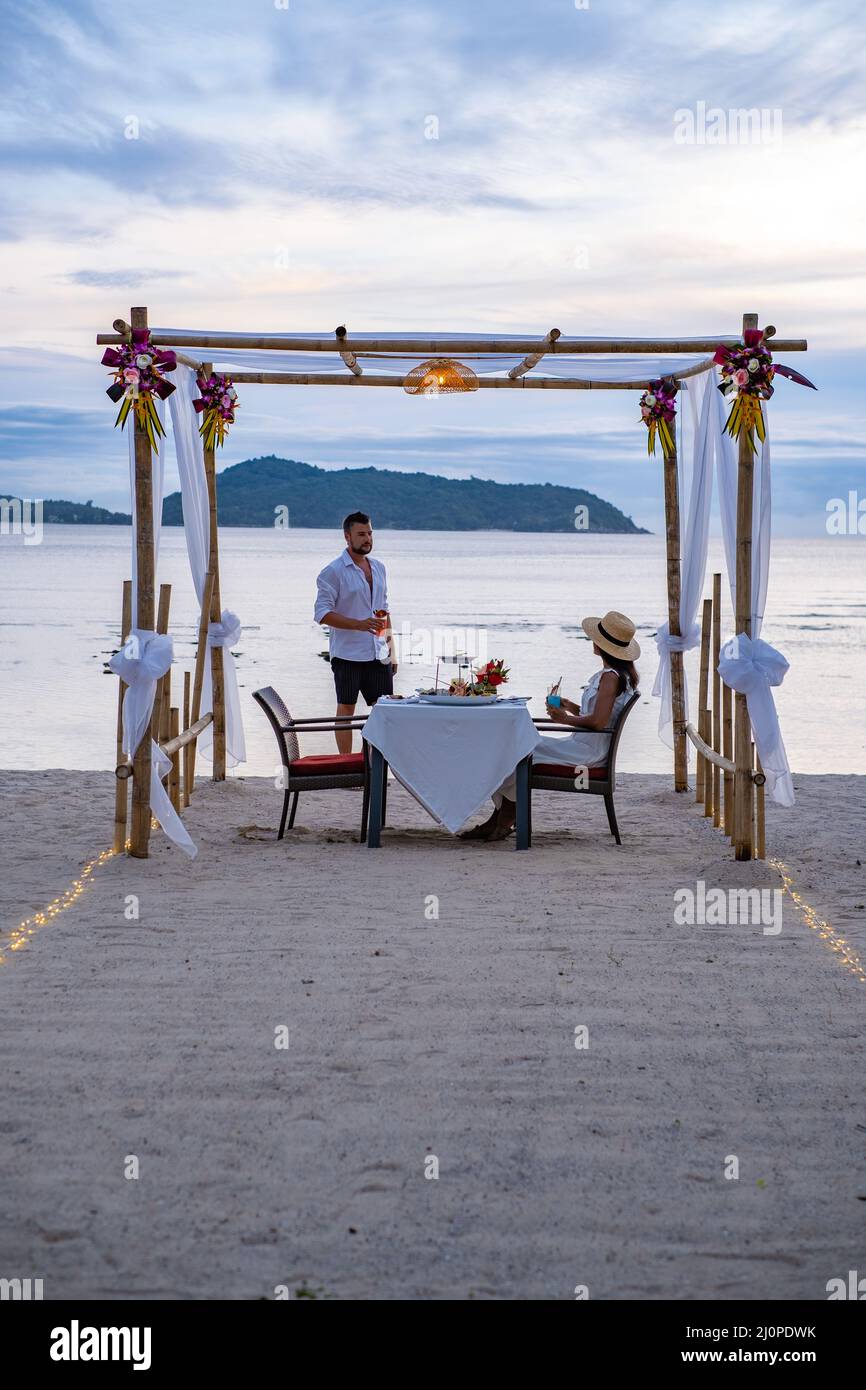Romantic dinner on the beach, couple man and woman mid age having a romantic dinner on the beach ...