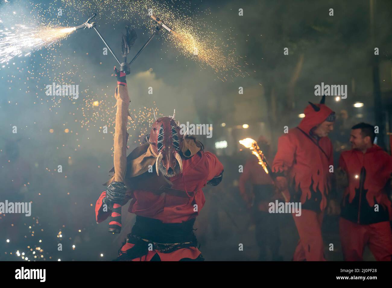 A person dressed as a demon holds firecrackers during the Parade of ...
