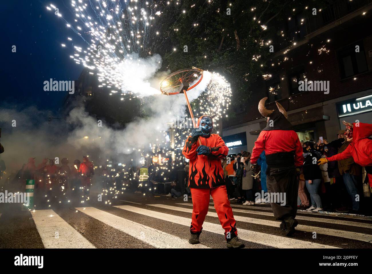 A person dressed as a demon holds firecrackers during the Parade of ...