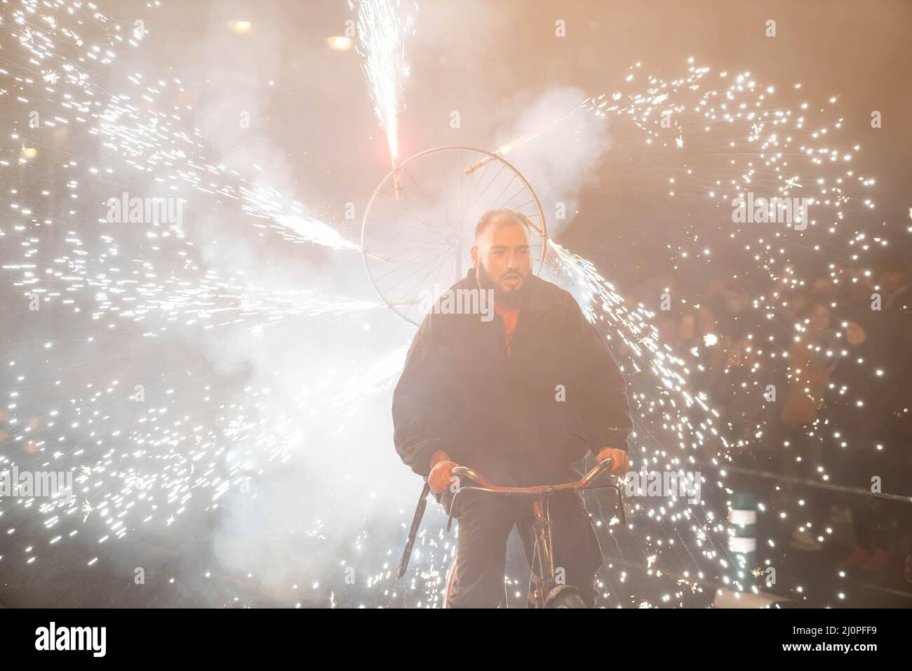 A man on a bicycle with fireworks during the Parade of Fire in Valencia ...