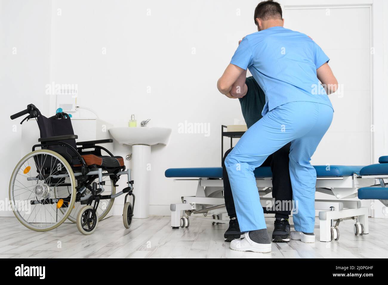 Male Physiotherapist helping a patient with a disability who uses a ...