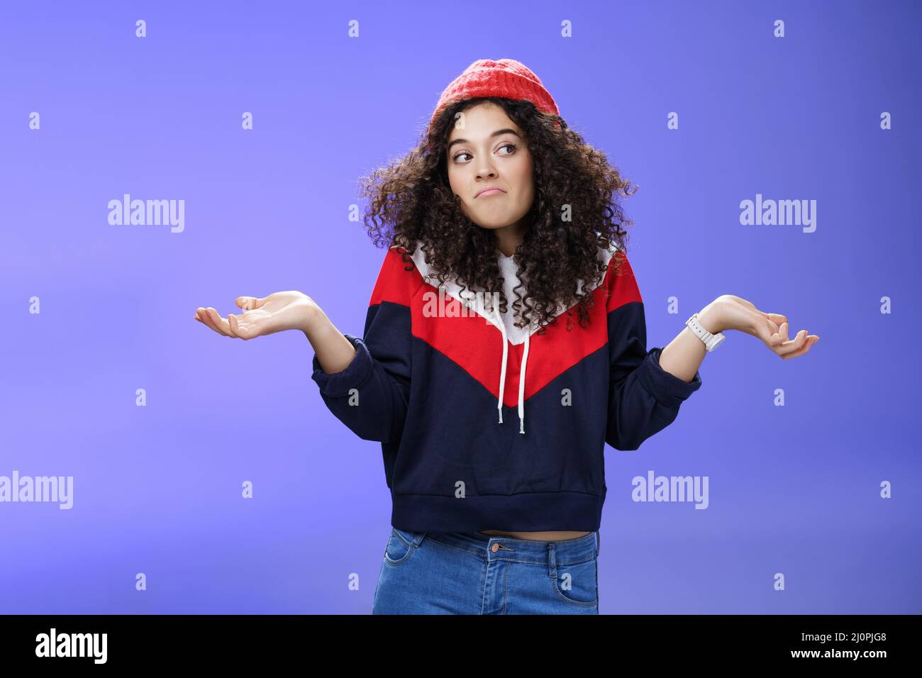 Not getting clue. Cute silly woman with curly hair shrugging with ...