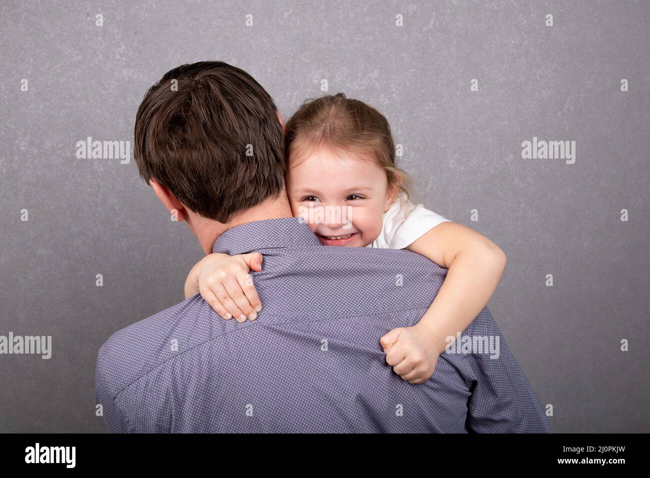 A little girl hugs her dad and smiles Stock Photo - Alamy