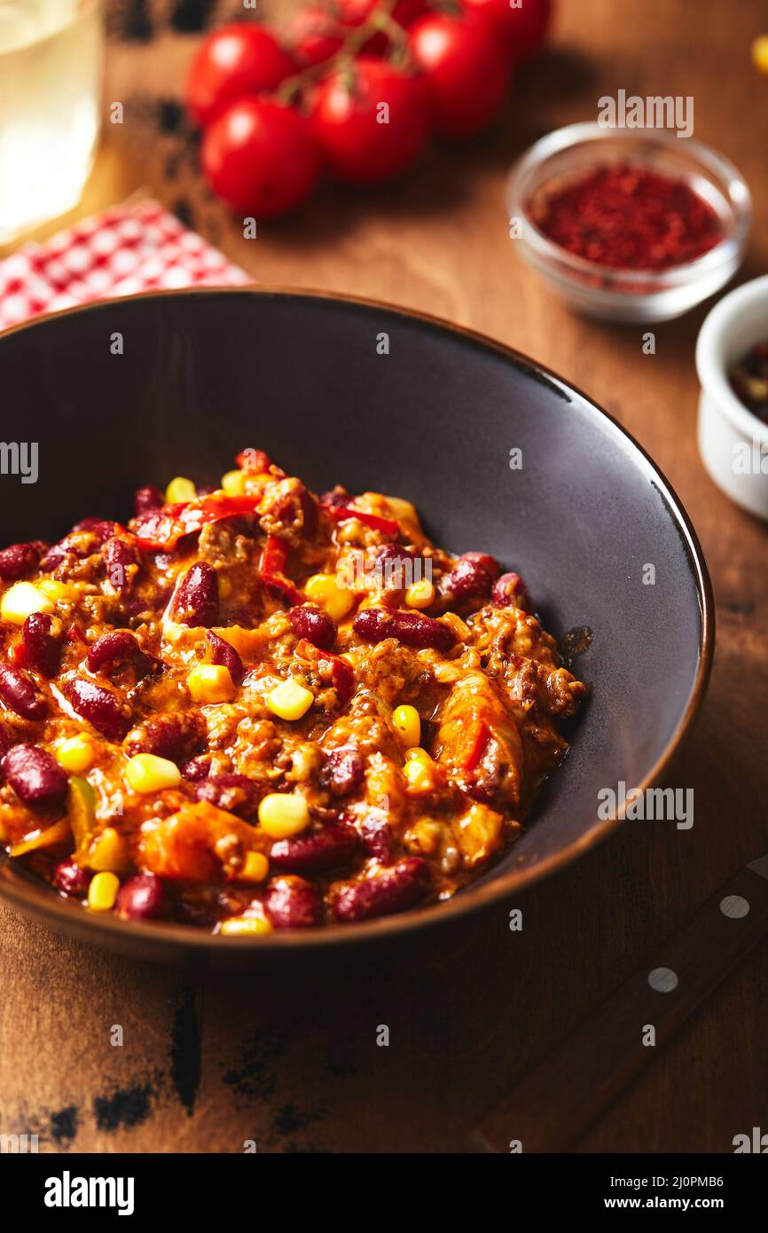 Chili Con Carne with ground beef, beans and corn in dark bowl on wooden ...