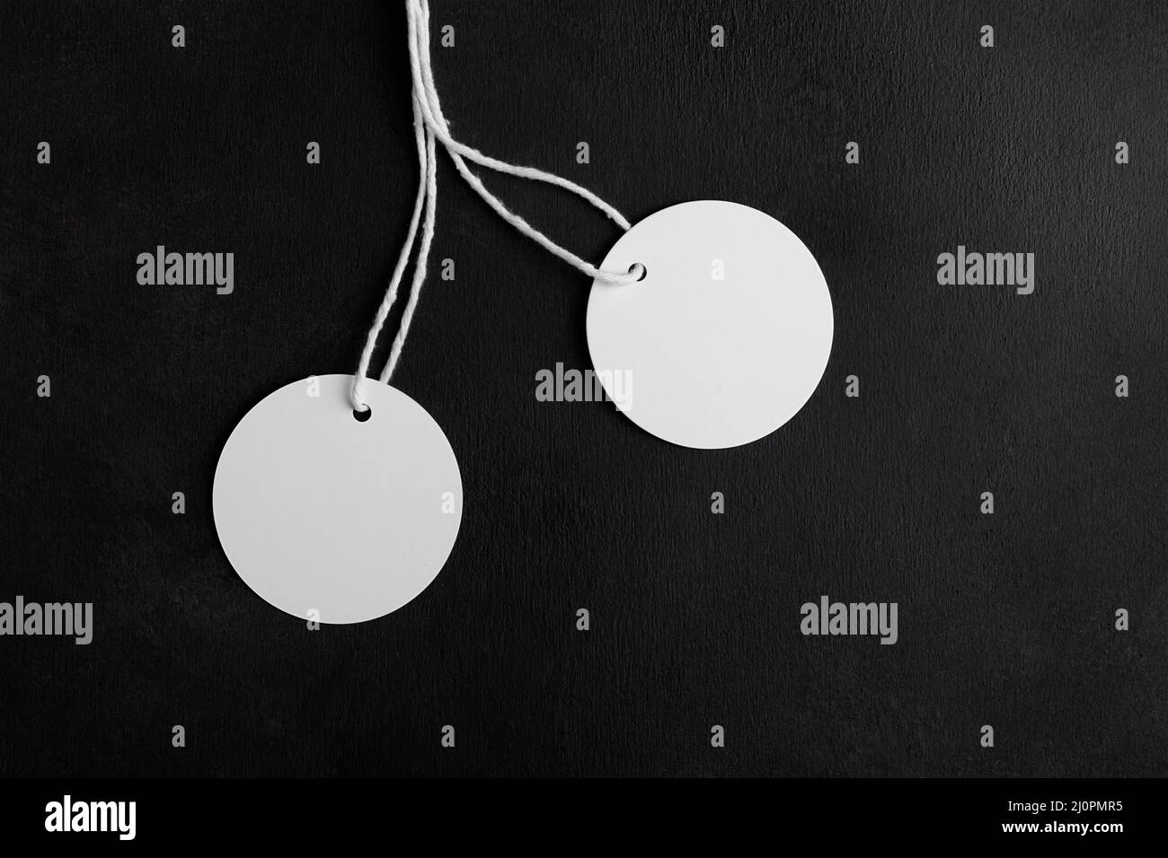 Two round white tag label mockups with white cord on black background ...