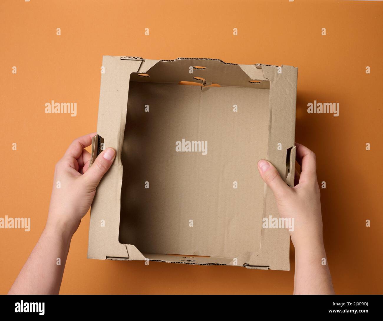 Female hands are holding an empty open box of brown cardboard, top view ...