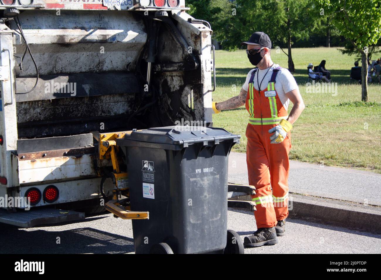Worker standing next to garbage truck Stock Photo - Alamy