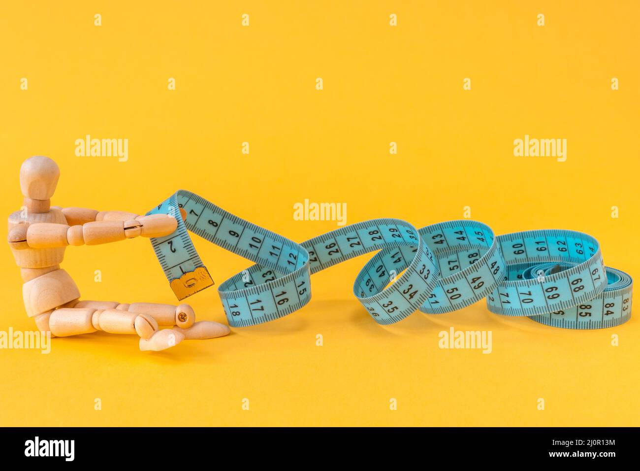 Wooden man pulling measure tape Stock Photo - Alamy