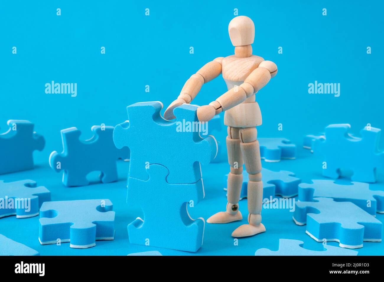 Wooden man assembling jigsaw puzzle Stock Photo - Alamy