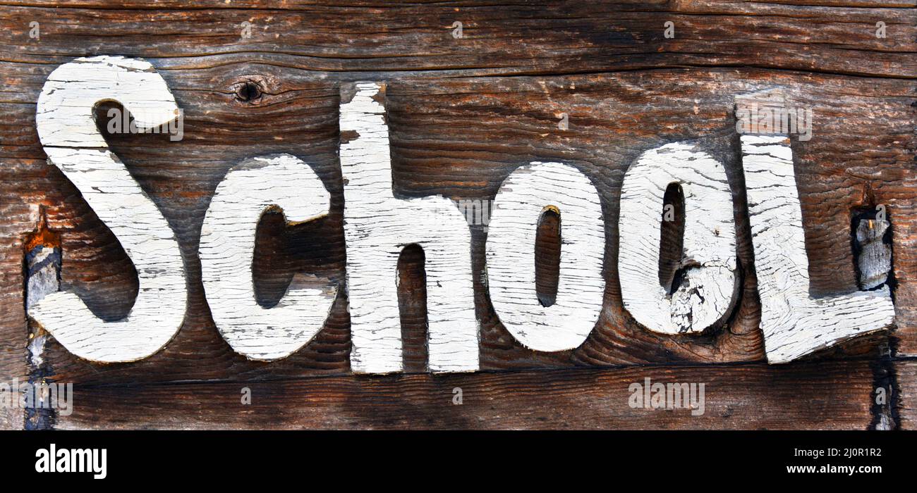 White, carve letters spell the word School on a wooden sign. Wood has ...