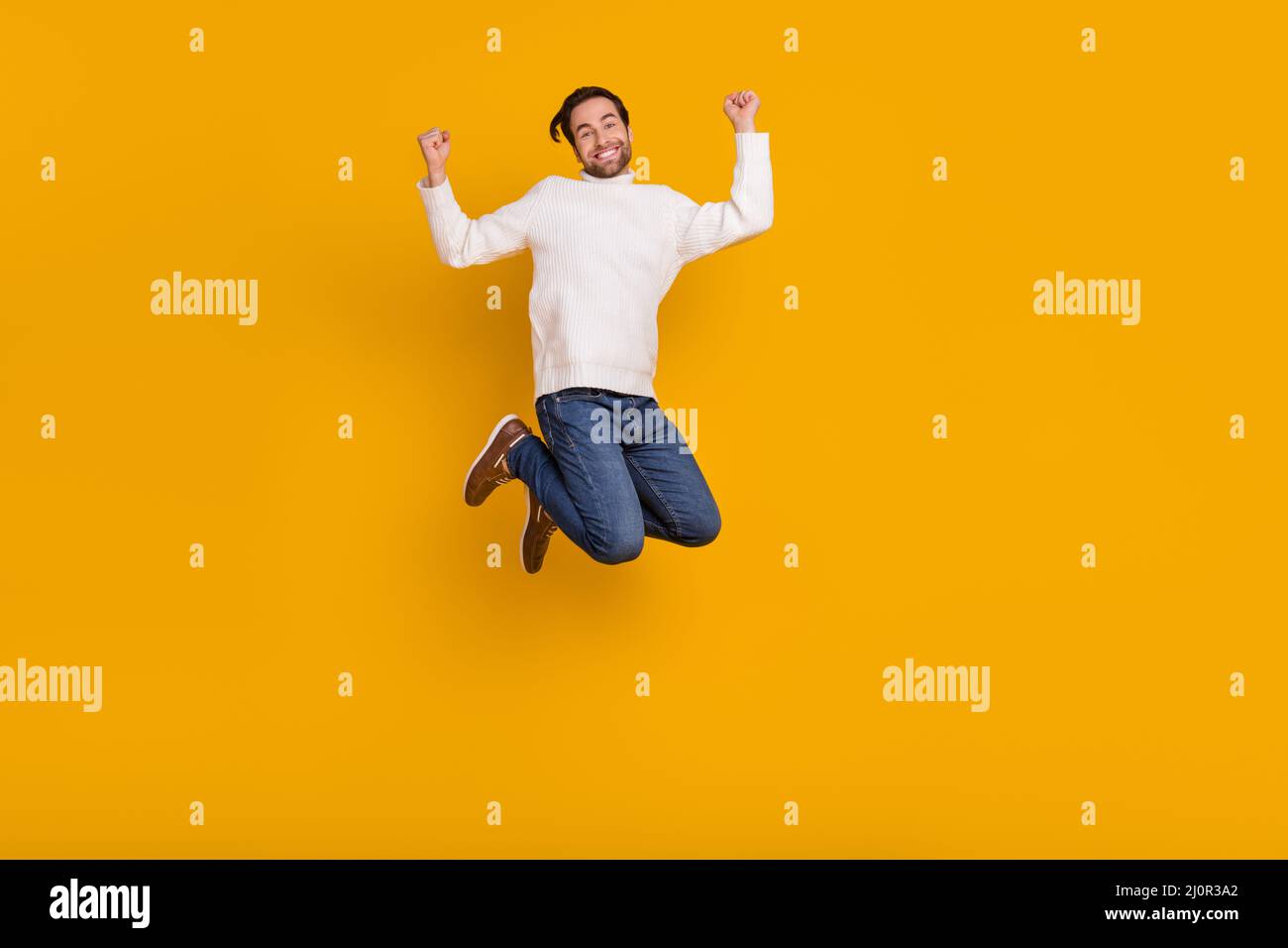 Photo of cheerful lucky guy dressed white sweater rising fists jumping ...