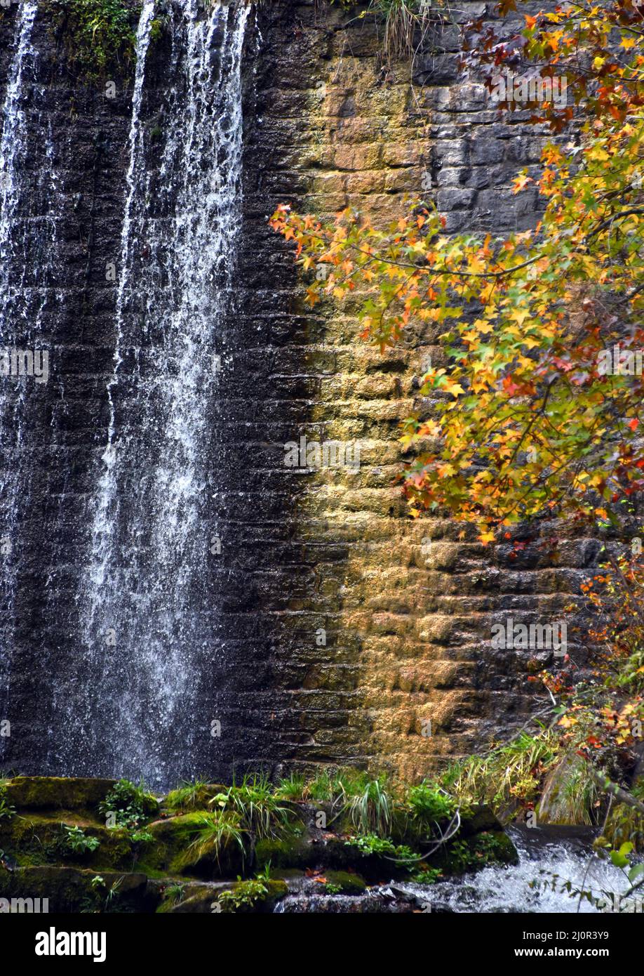 Mirror Lake Dam has colorful stone wall. Yellow and orange Fall leaves ...