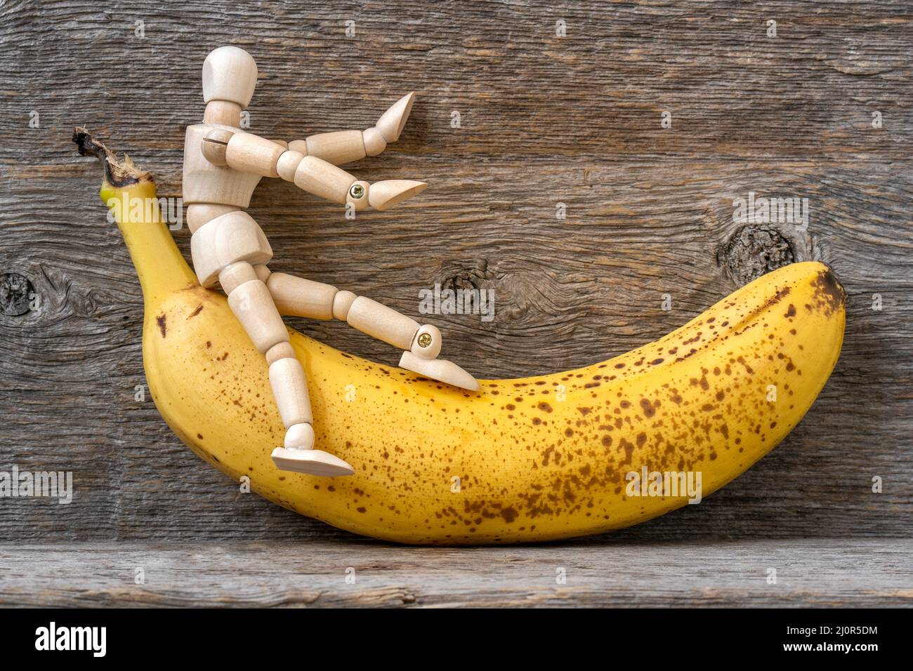 Wooden man sitting on the healthy yellow banana Stock Photo - Alamy