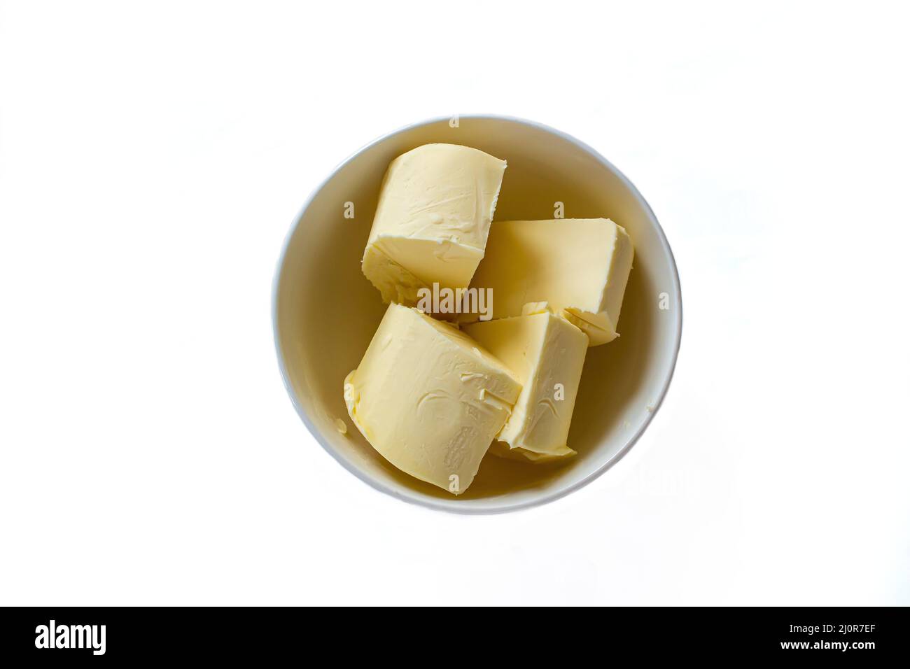 Butter pieces in bowl, isolated on white background. Top view of ...